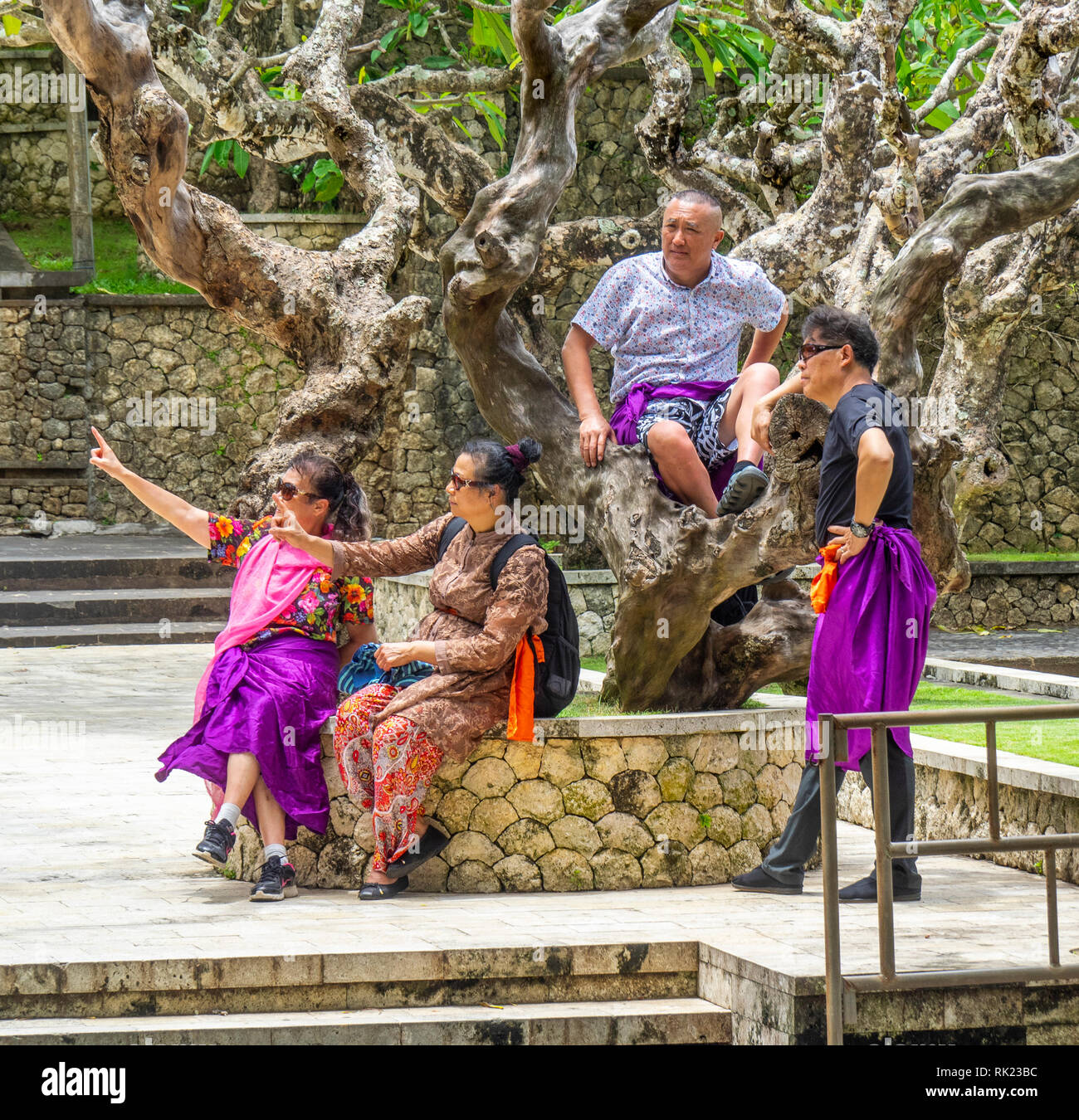 Chinese tourists wearing purple sarongs visiting Uluwatu Temple Bali ...