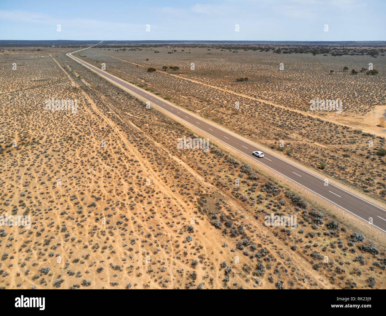 Aerial of single car travelling through the blue bush country on the ...