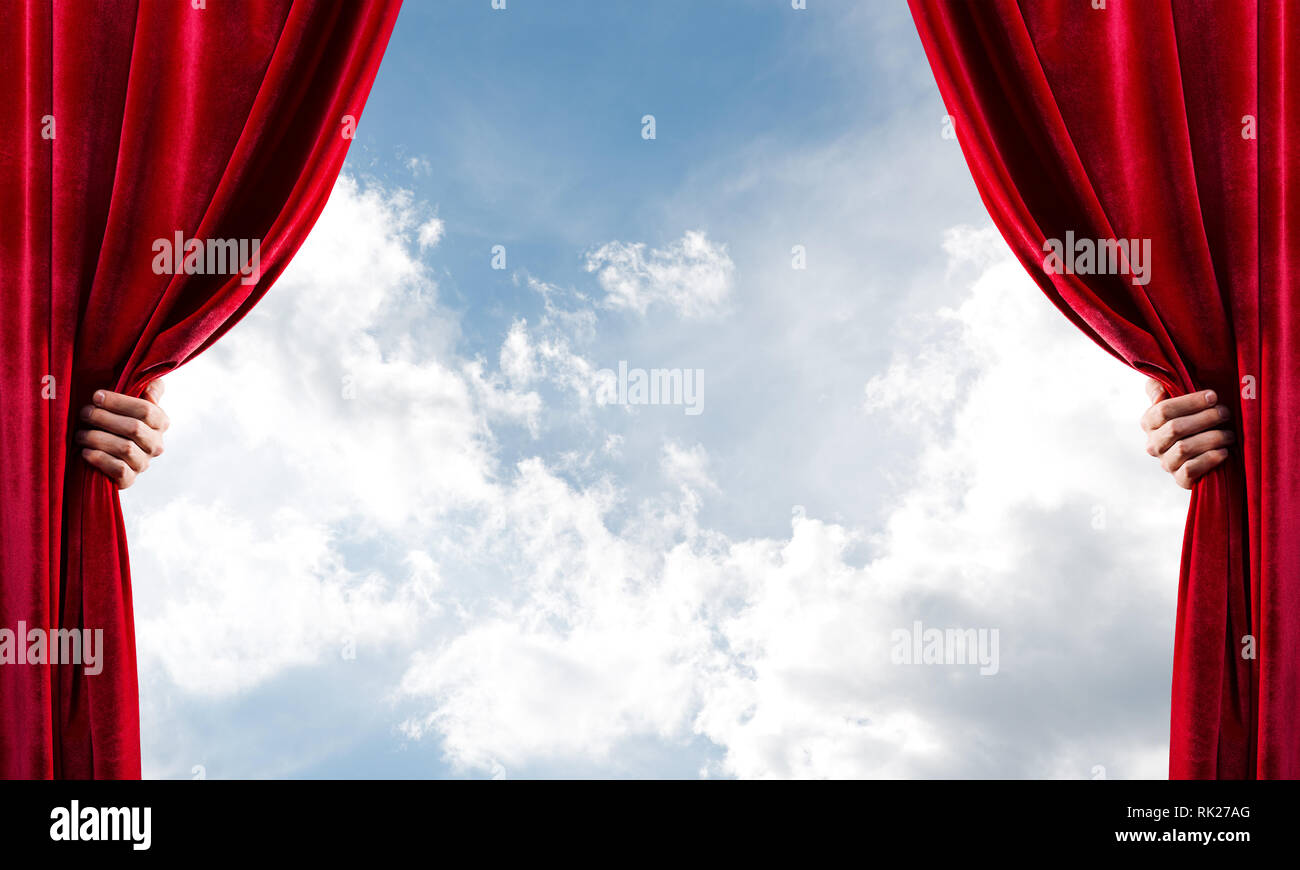 Cloudy landscape behind red curtain and hand holding it Stock Photo - Alamy