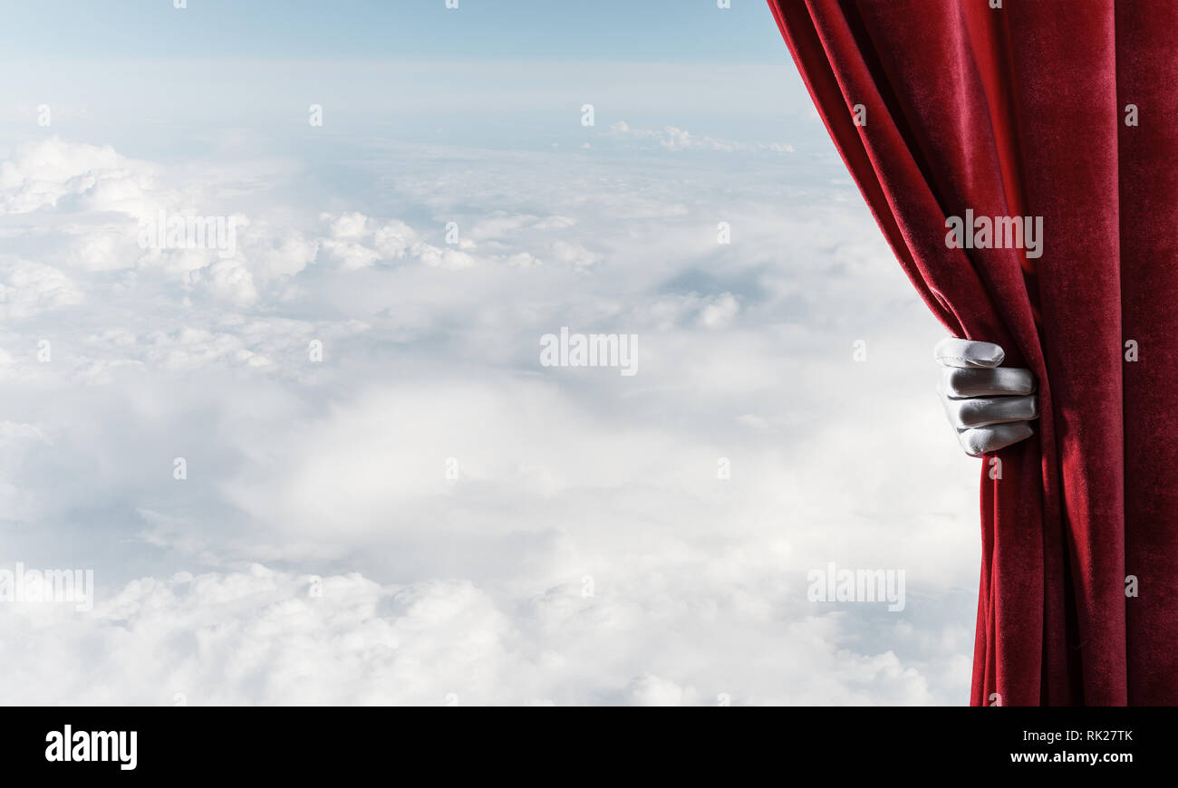 Cloudy landscape behind red curtain and hand holding it Stock Photo - Alamy
