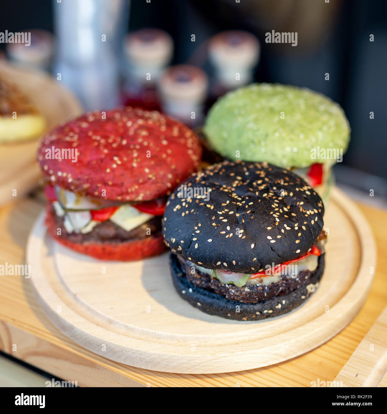 Three tasty bright multicolored beef burgers on wooden counter at food ...