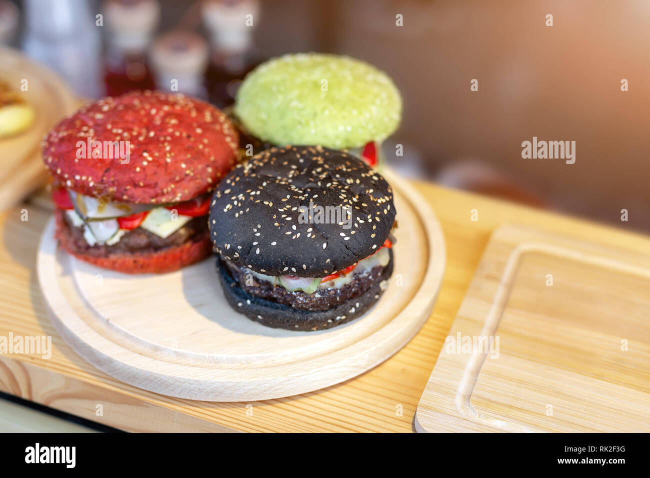 Three tasty bright multicolored beef burgers on wooden counter at food ...