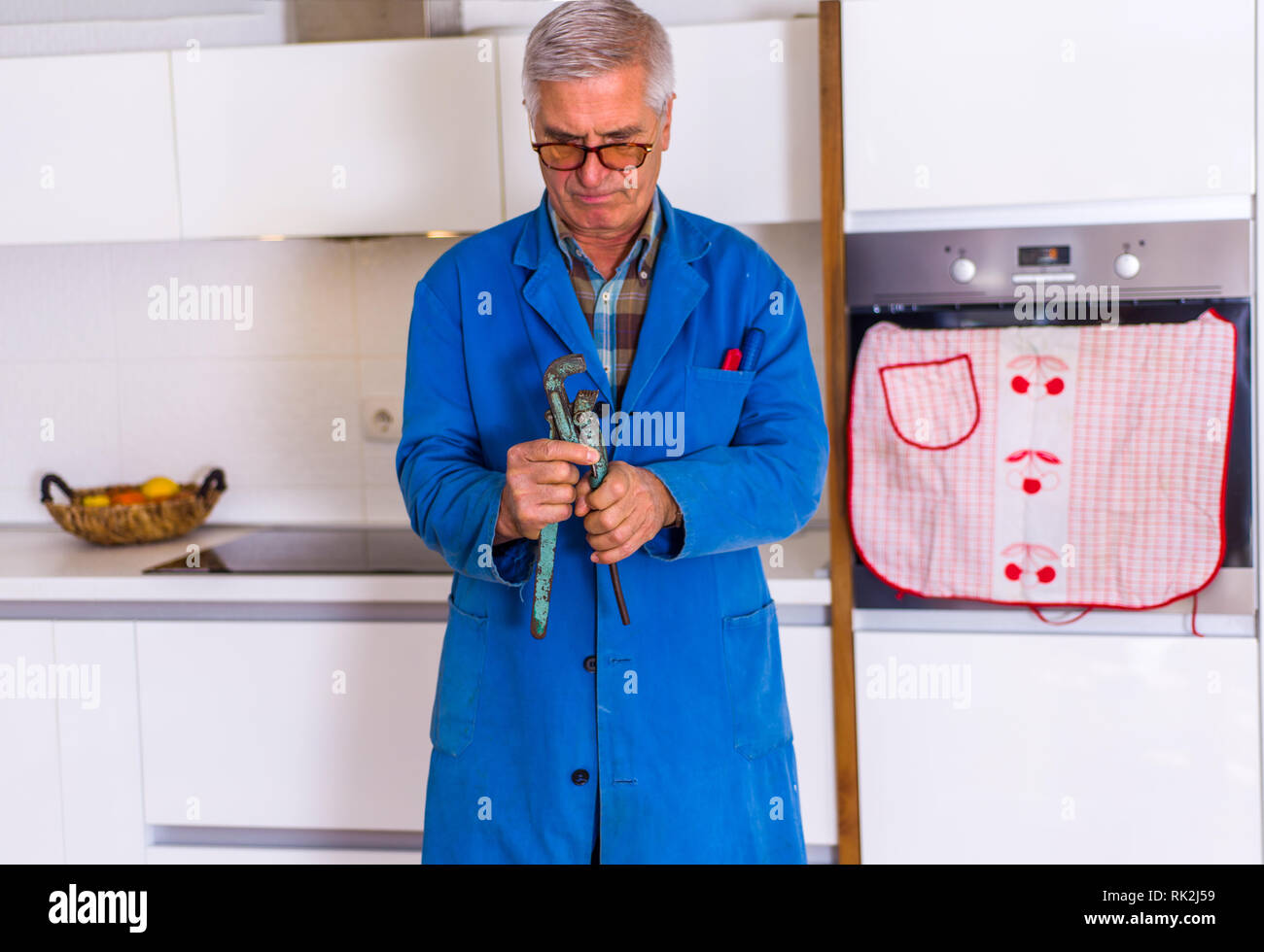Old age handyman holding his tool in the kitchen and working Stock ...