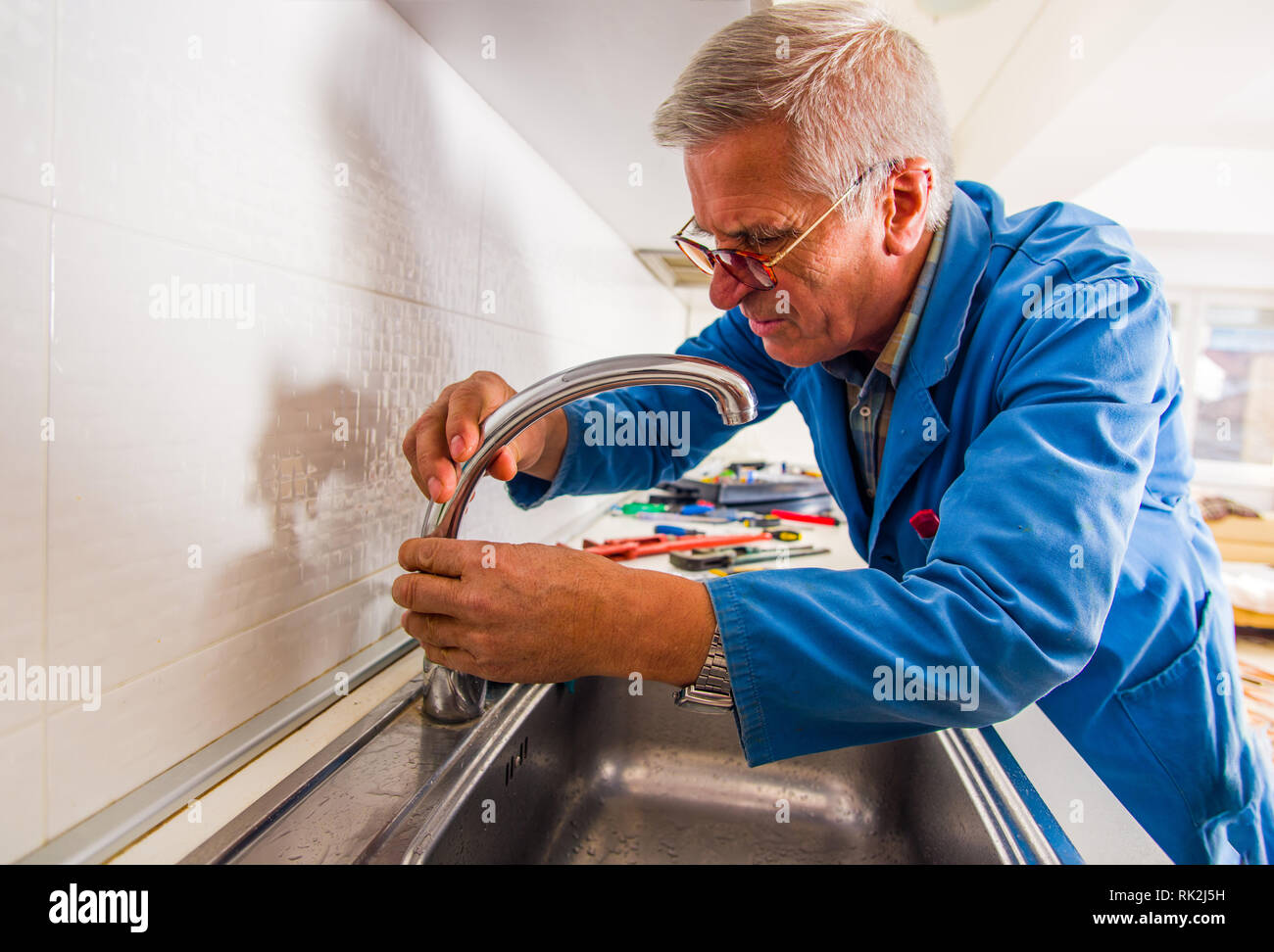Old male repairman is fixing the kitchen tap Stock Photo - Alamy
