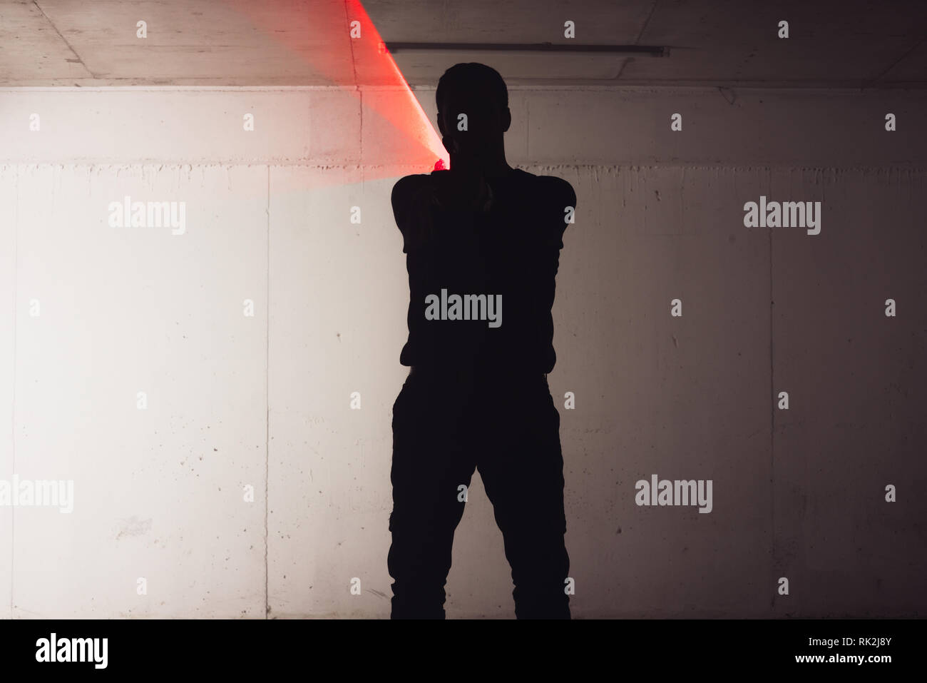 silhouette of an armed man holding his gun and pointing with his laser ...
