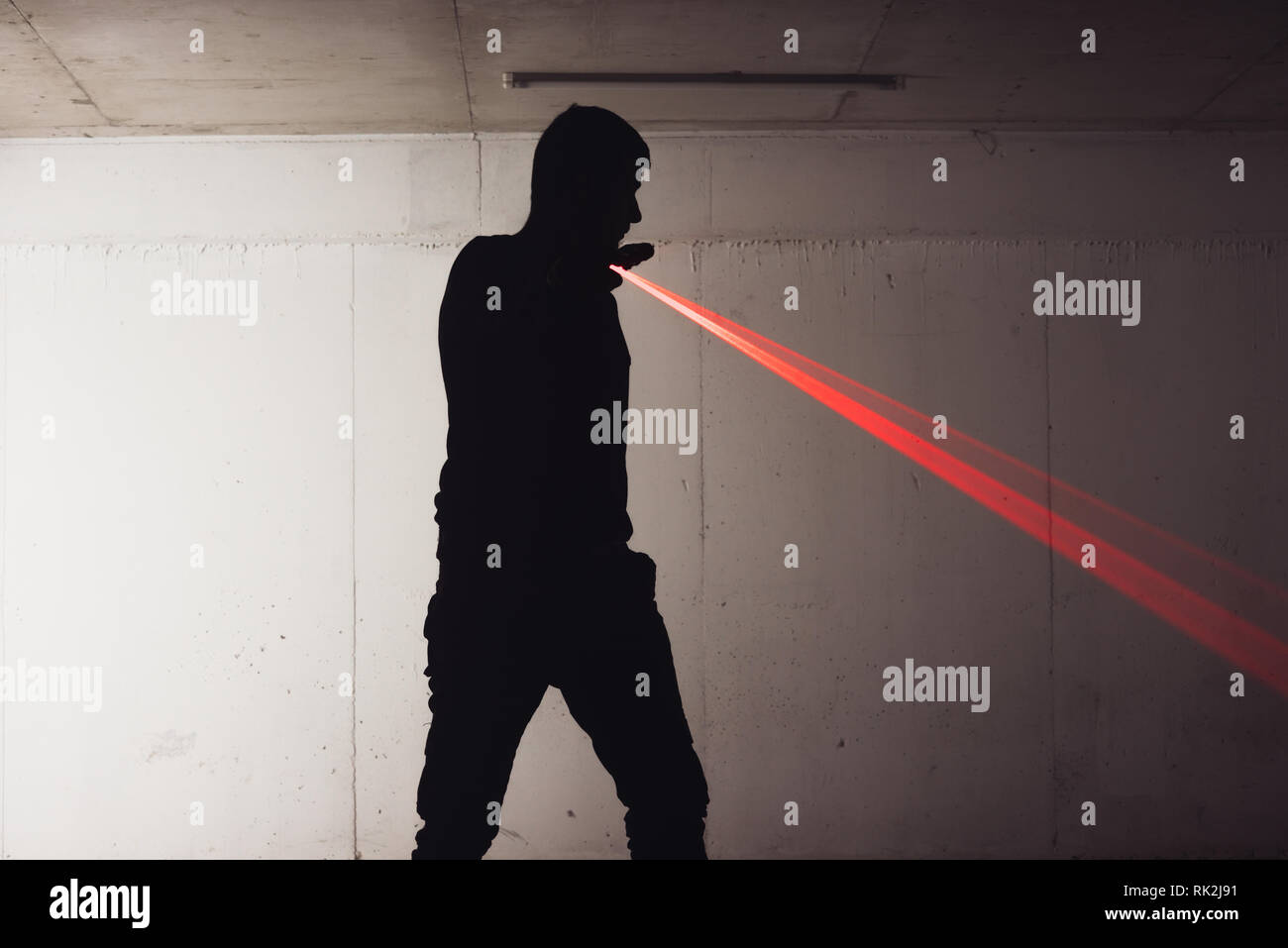 silhouette of an armed man holding his gun and pointing with his laser ...