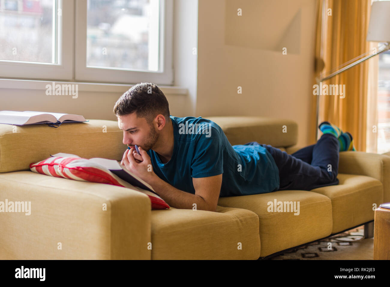 A handsome young man is looking relaxed while studying from book Stock ...