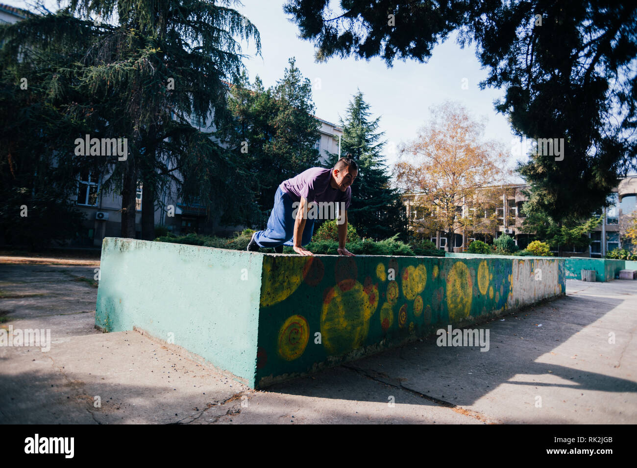 Athletic Parkour Guy Doing Backflip And Tricks While Jumping Off And Over A Concrete Wall Stock