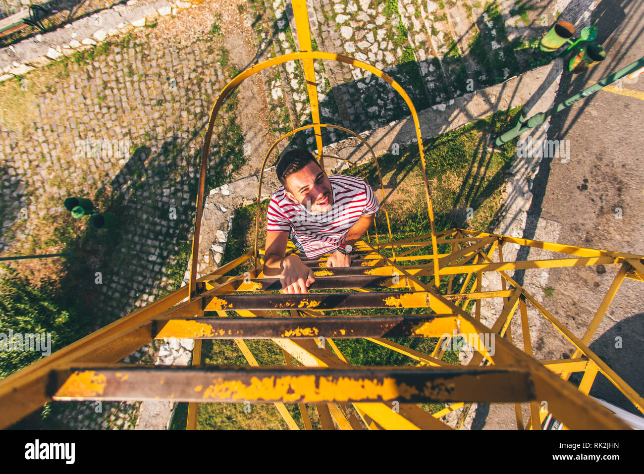 Friends trying to reach the top on metal construction, climbing ladder ...
