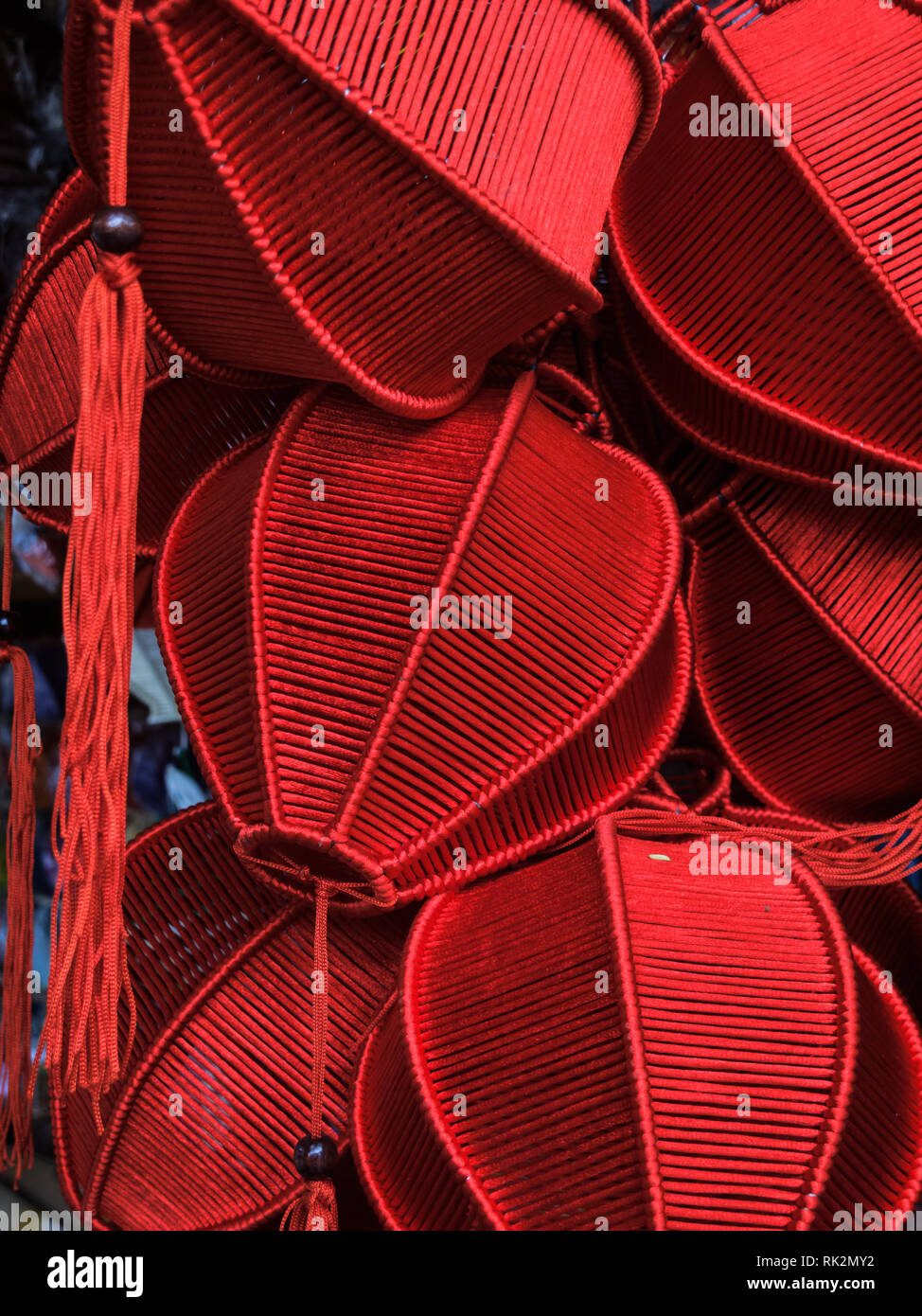 Two people wearing conical hats sit by a river next to a boat in front ...