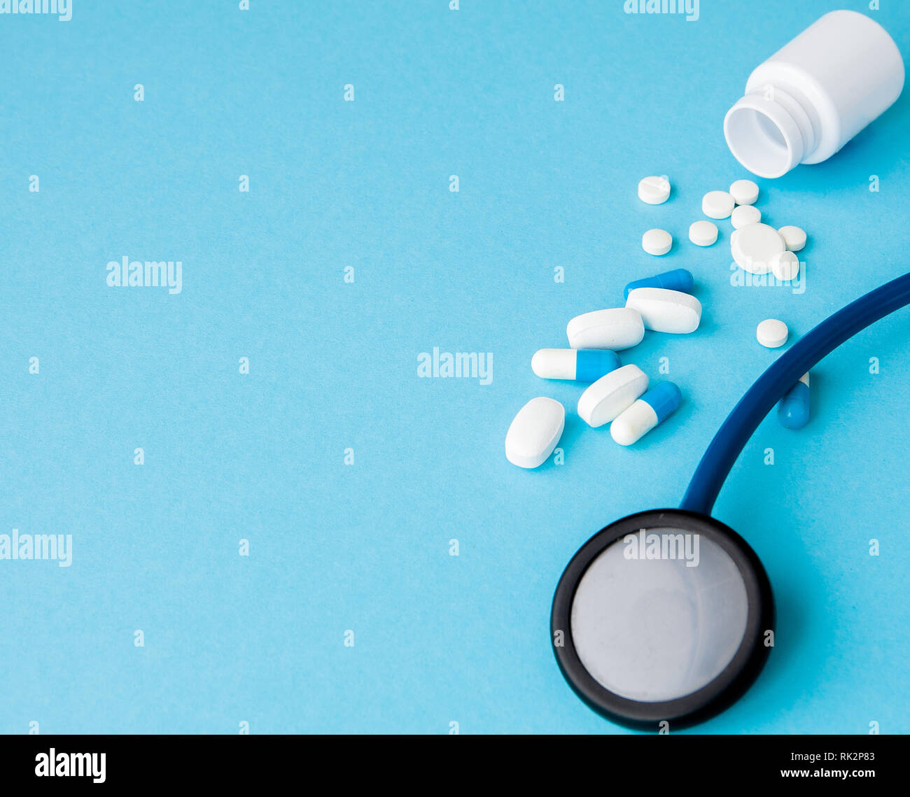 Close Up Stethoscope And Pills Spilling Out Of Pill Bottle On Blue