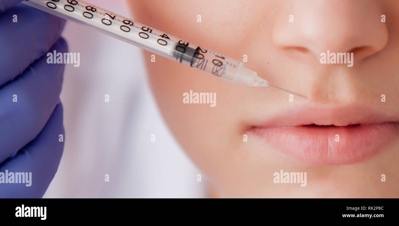 Doctor in gloves giving woman botox injections in lips, on pink ...
