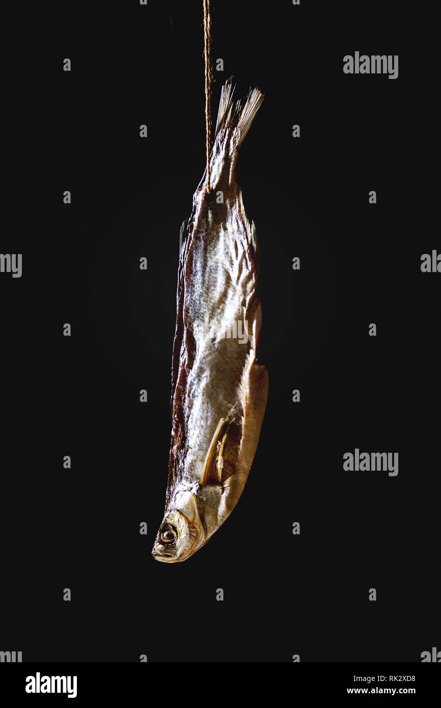 Dried fish or stockfish on thread over dark wooden background Stock ...