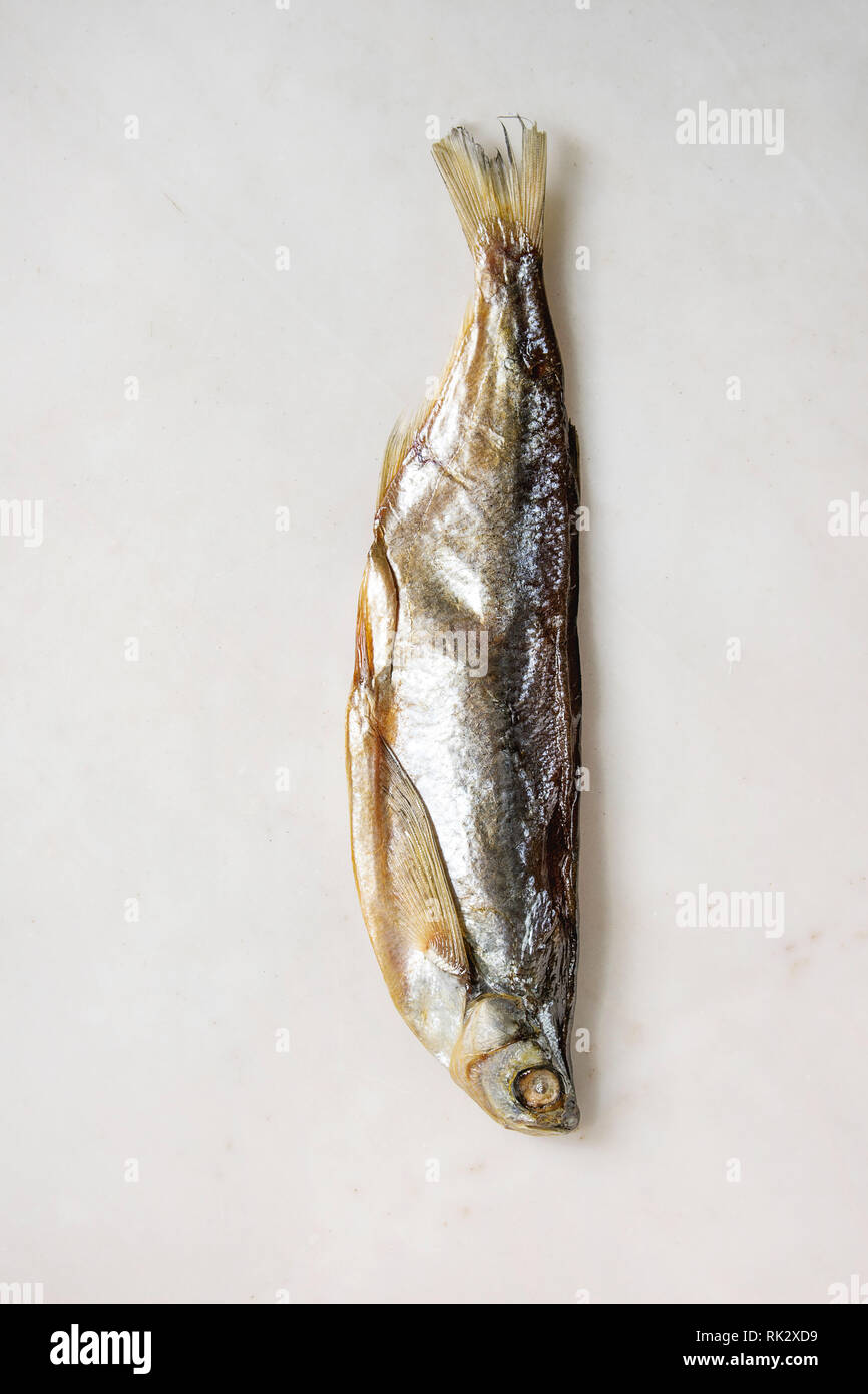 Dried fish or stockfish over white marble background. Flat lay, space ...
