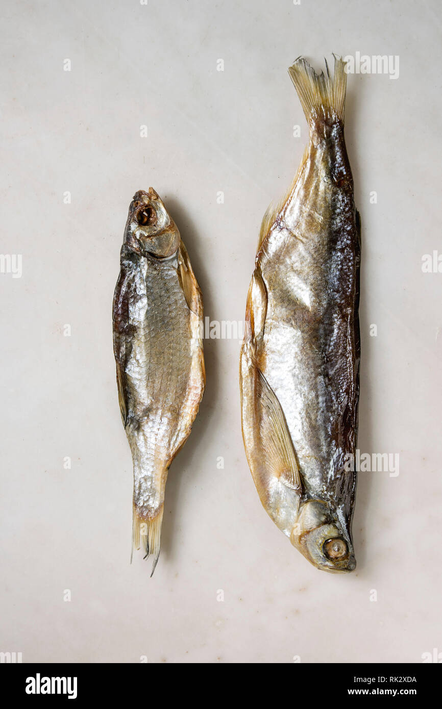 Dried fish or stockfish over white marble background. Flat lay, space ...