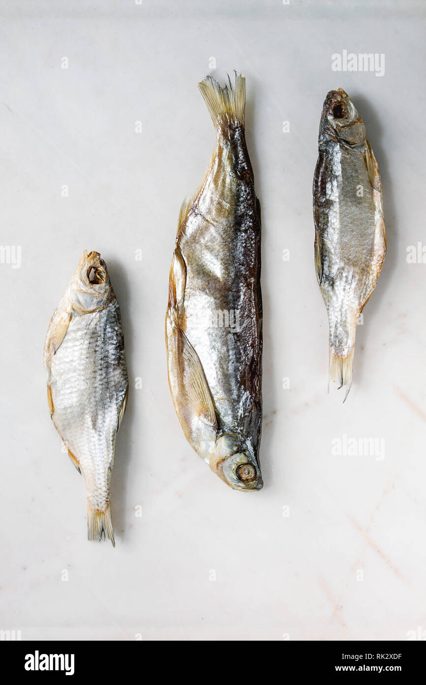 Dried fish or stockfish over white marble background. Flat lay, space ...