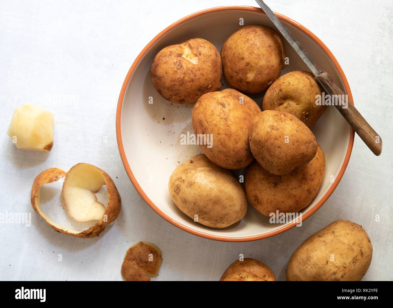 Brushed potatoes in a bowl with one peeled potato Stock Photo - Alamy