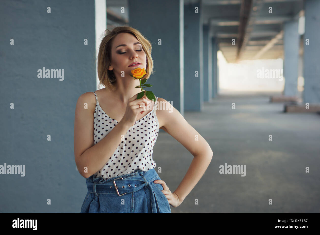 Young attractive girl holding yellow rose flower in her hands. Spring ...