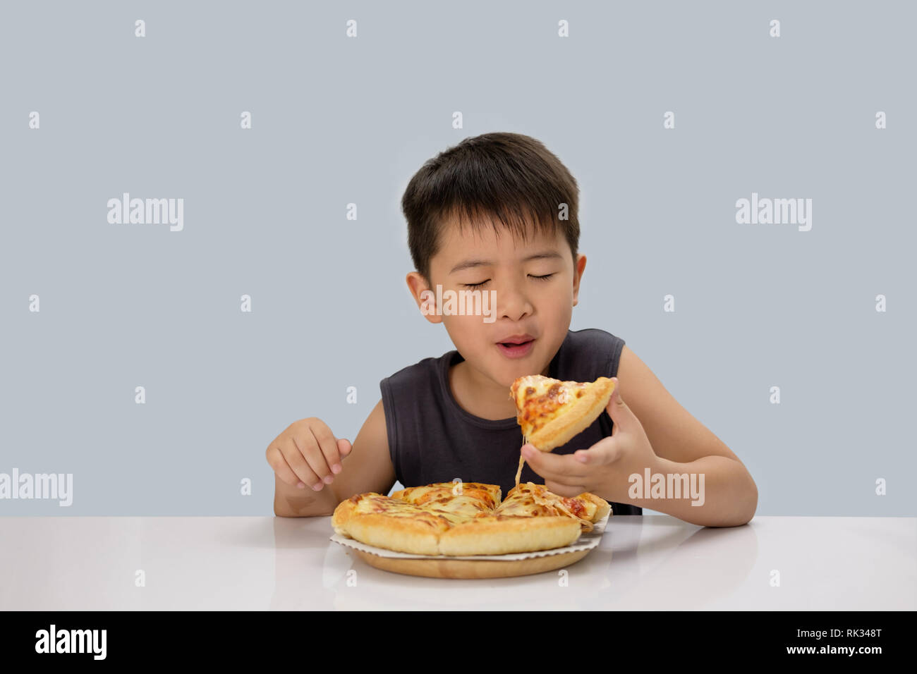 Cute boy eating pizza isolated on blue background Stock Photo - Alamy