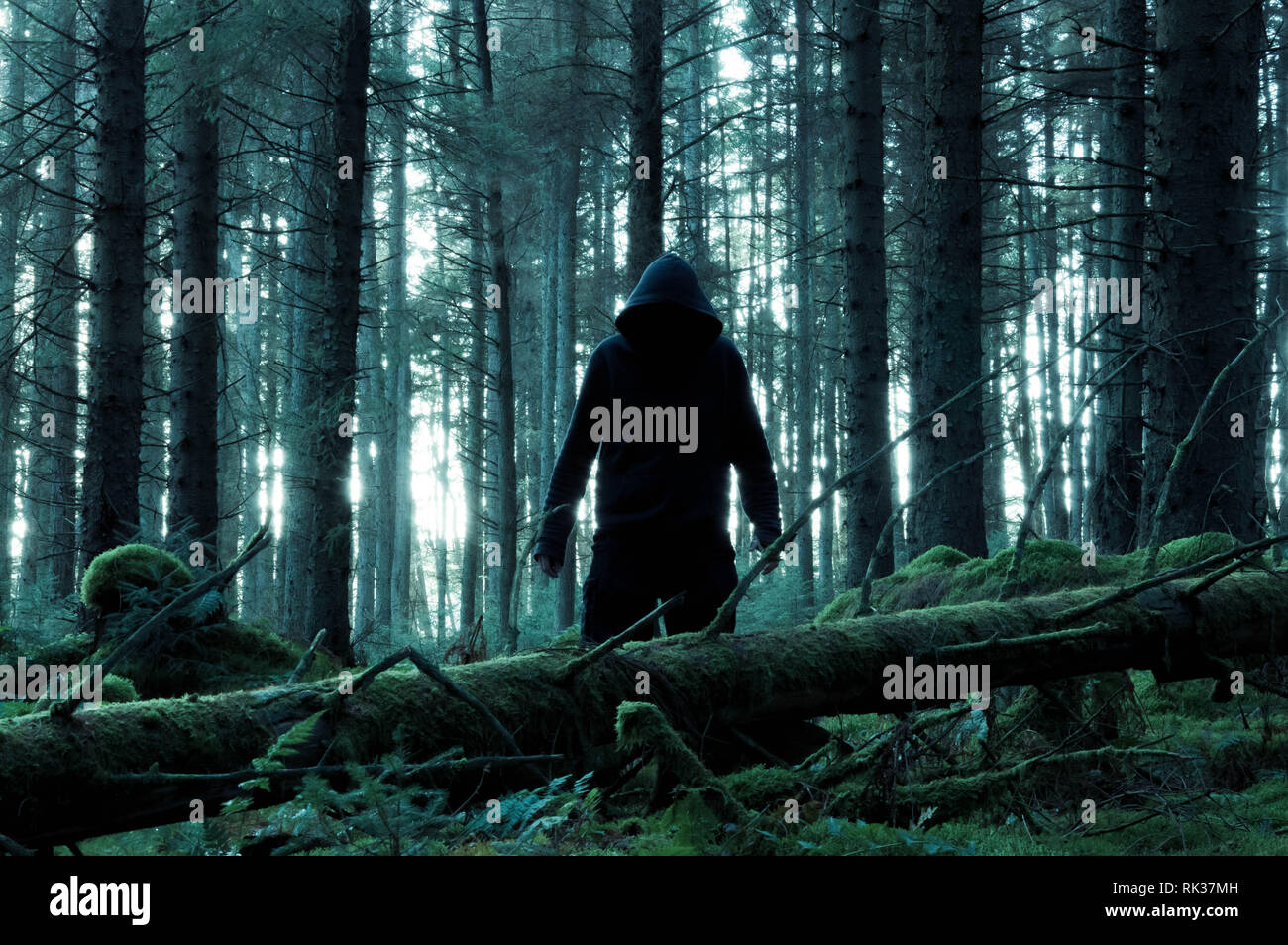 A lone sinister hooded figure looking at the camera standing in a ...