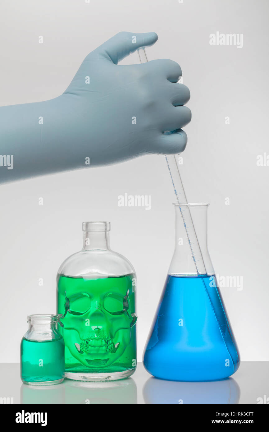 A hand in laboratory gloves mixes chemistry. Liquid in laboratory ...