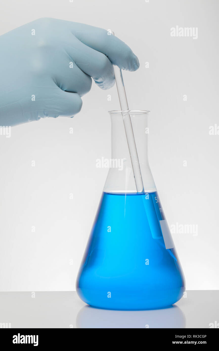A hand in laboratory gloves mixes chemistry. Liquid in laboratory ...
