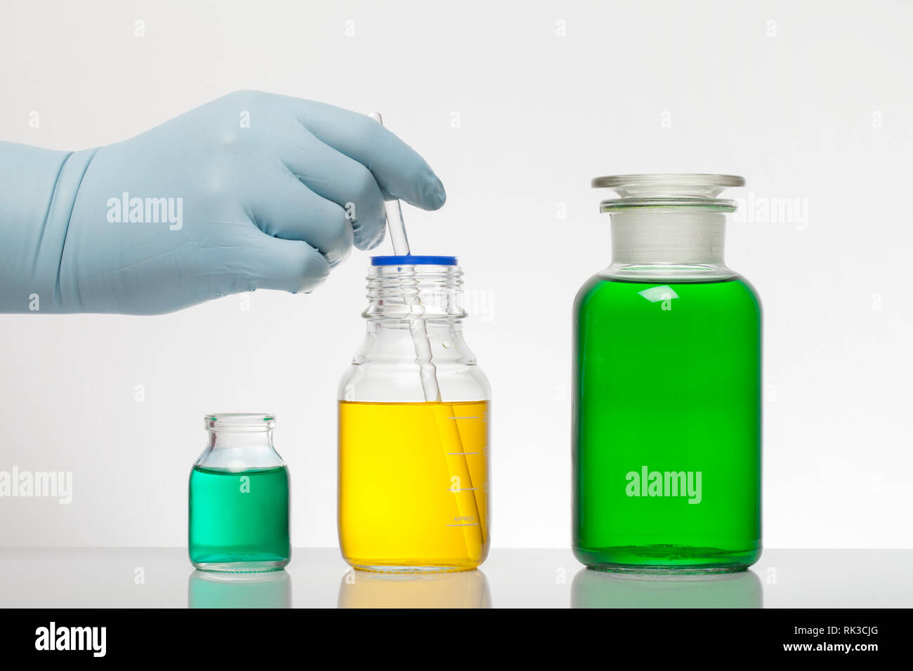 A hand in laboratory gloves mixes chemistry. Liquid in laboratory ...