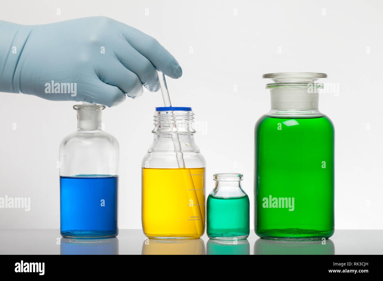 A hand in laboratory gloves mixes chemistry. Liquid in laboratory ...