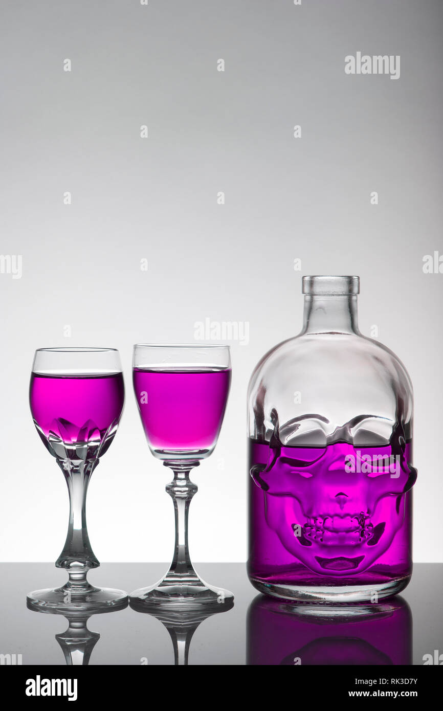 A skull bottle and crystal glasses with a liquid, alcohol drink ...