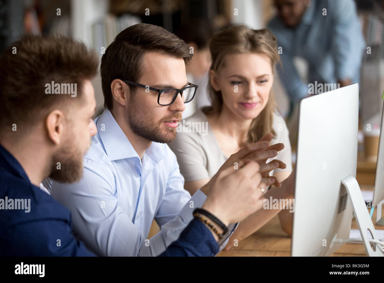 Serious employees working together discussing computer task in office ...