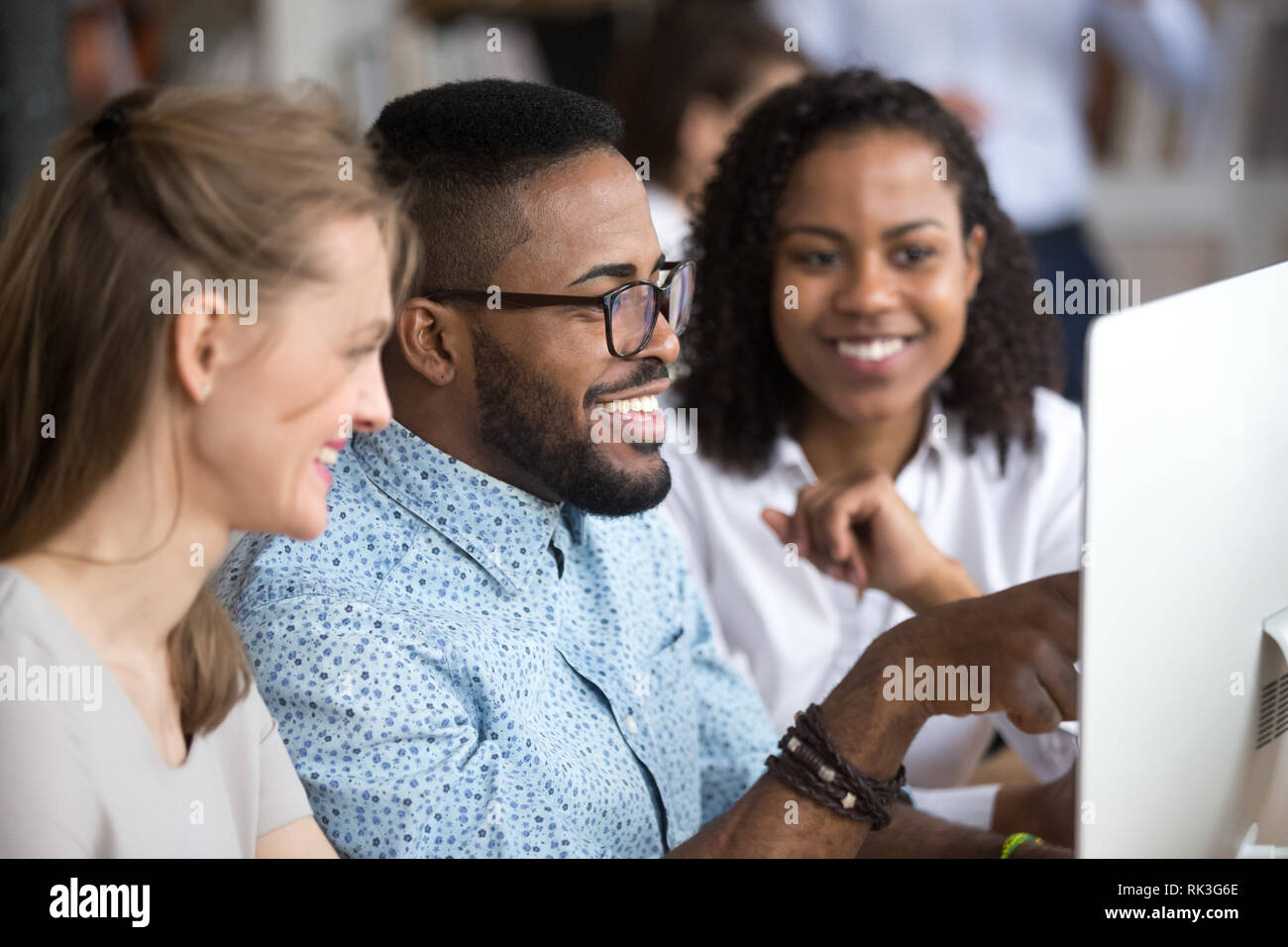 Smiling african team leader explaining computer task to employees group ...
