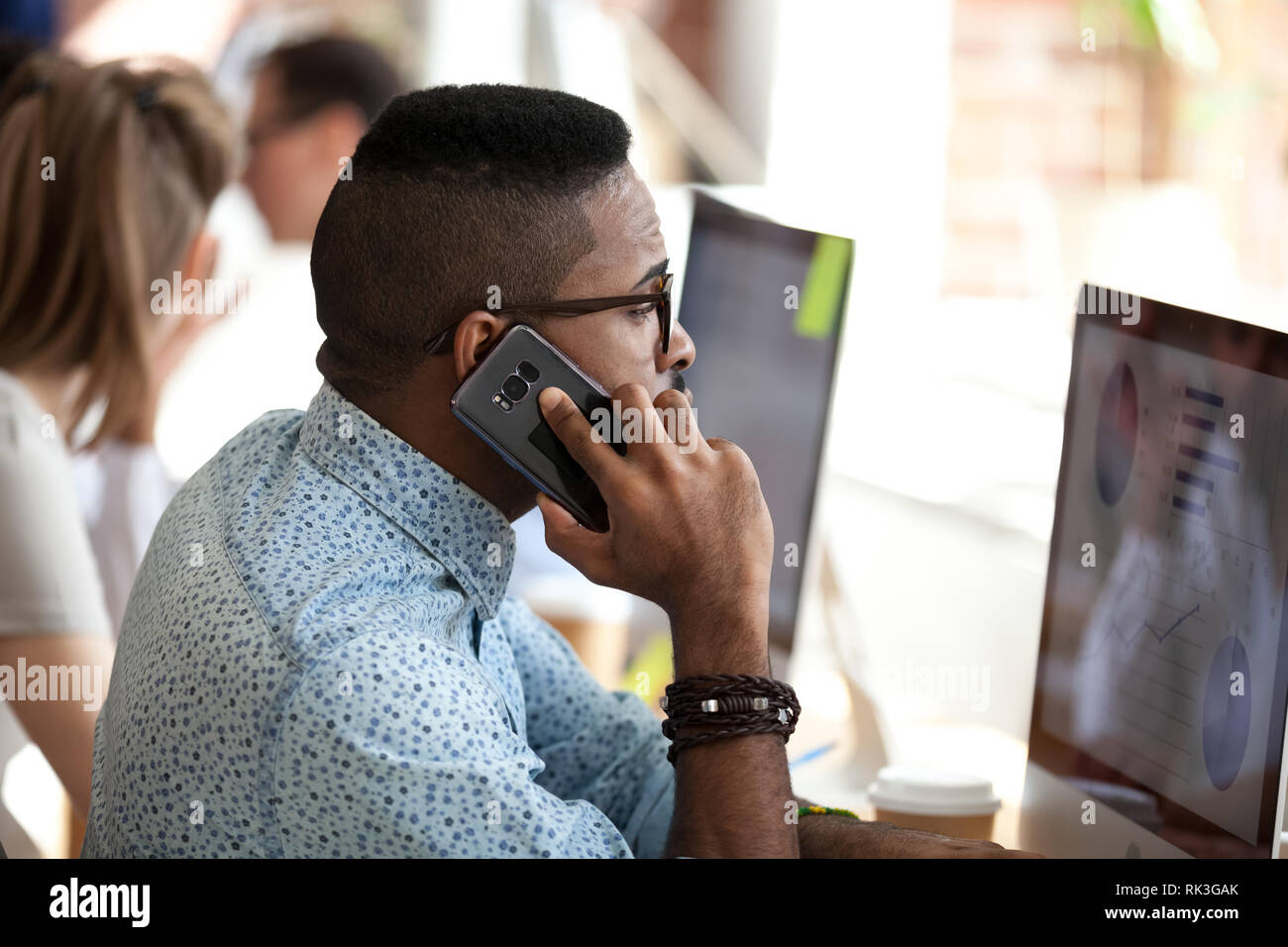 Serious african employee talking on phone consulting client in office ...