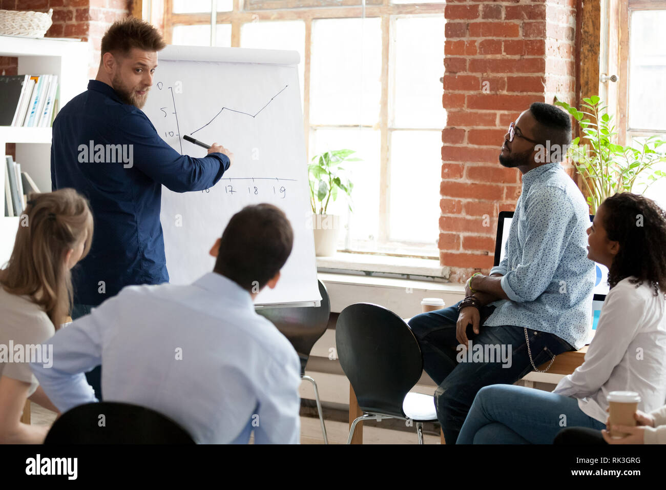 Serious executive presenter gives presentation on whiteboard to ...