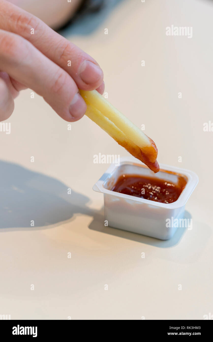 Close-up of female hand dipping fries in tomato sauce. Hand with fresh ...