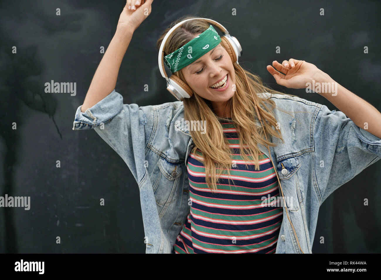 Dynamic young student dancing to music with headphones on black ...