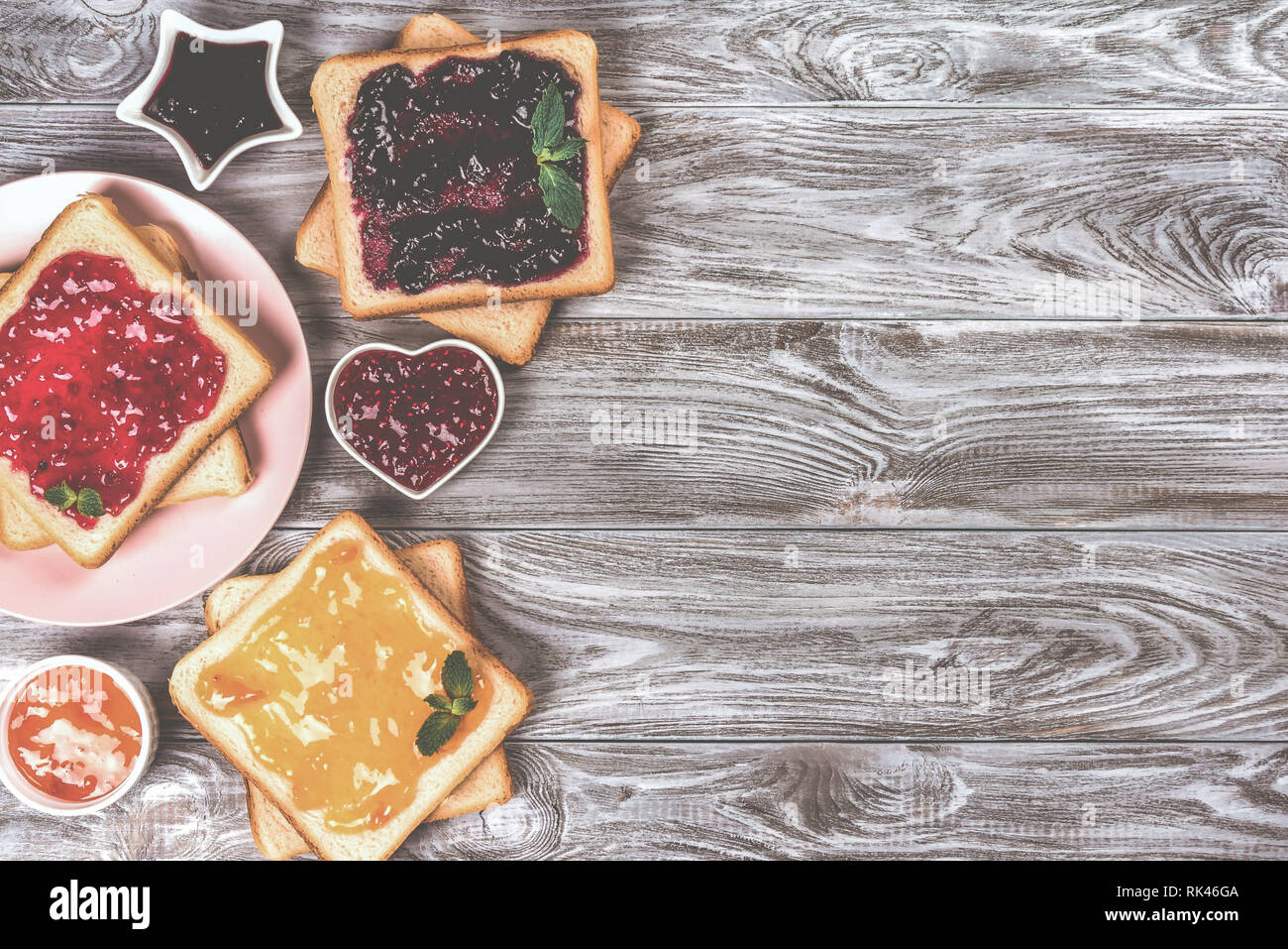 Delicious toasts with various sweet jams on grey background. Copyspace ...