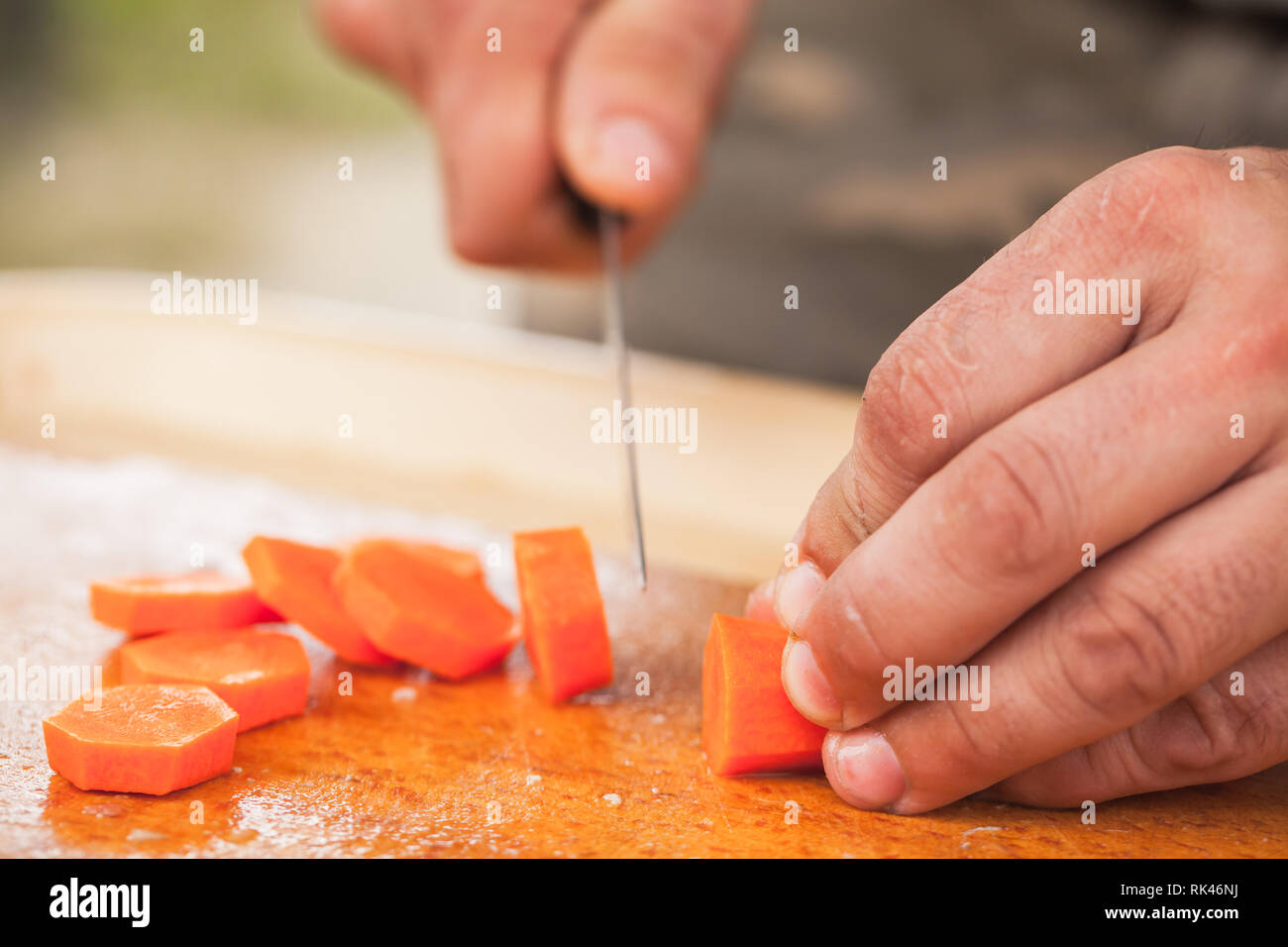 Carrot slicing. Cook hands with knife, close-up photo with selective ...