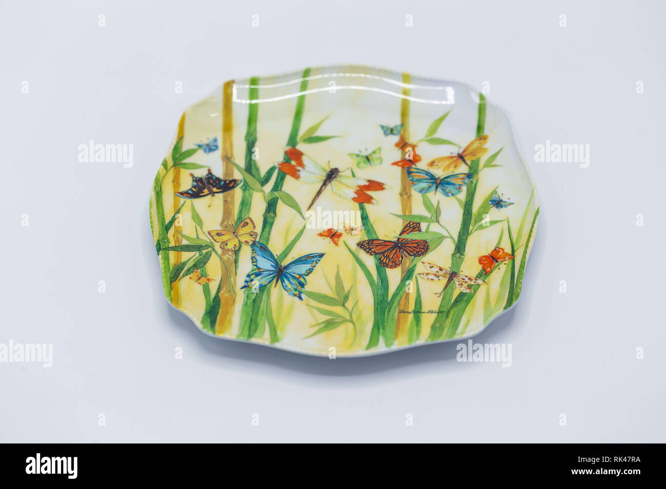 a small white decorative plate with flowers and butterflies on it Stock ...