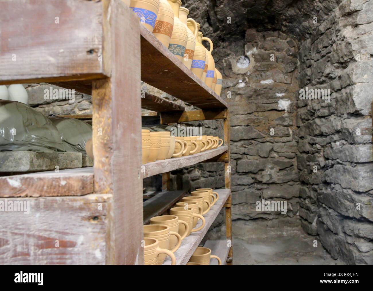 handcrafted clay pots and cups sitting on display on wood shelves in an ...