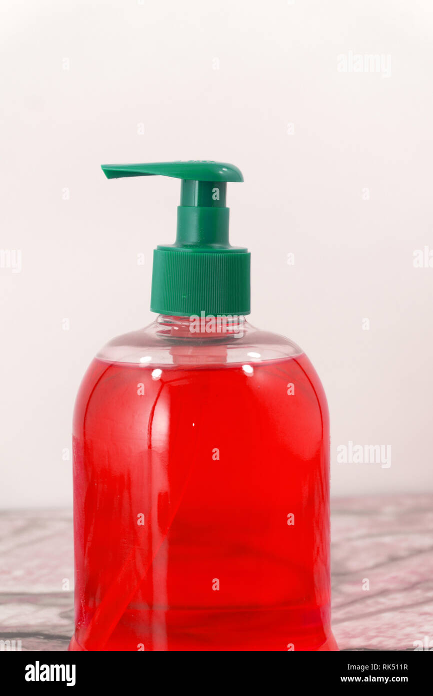 Bath accessory. Bottle of red liquid soap with drops of water isolated ...