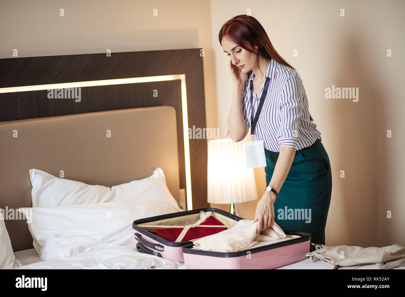Female hotel guest in formal wear packing her suitcase, leaving hotel ...