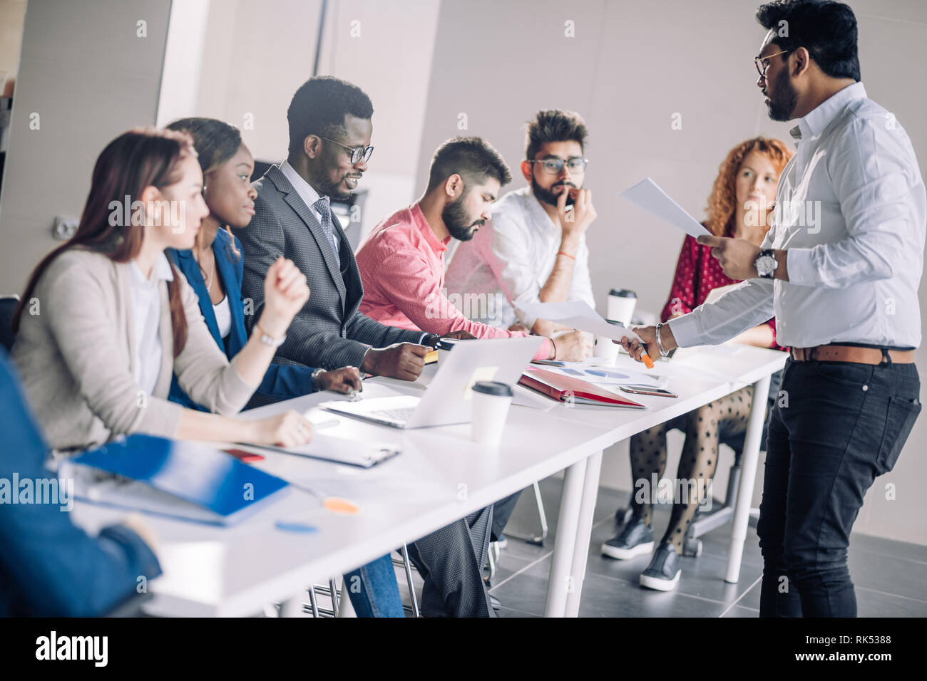 Indian man handing out paper tests to his international co-workers ...