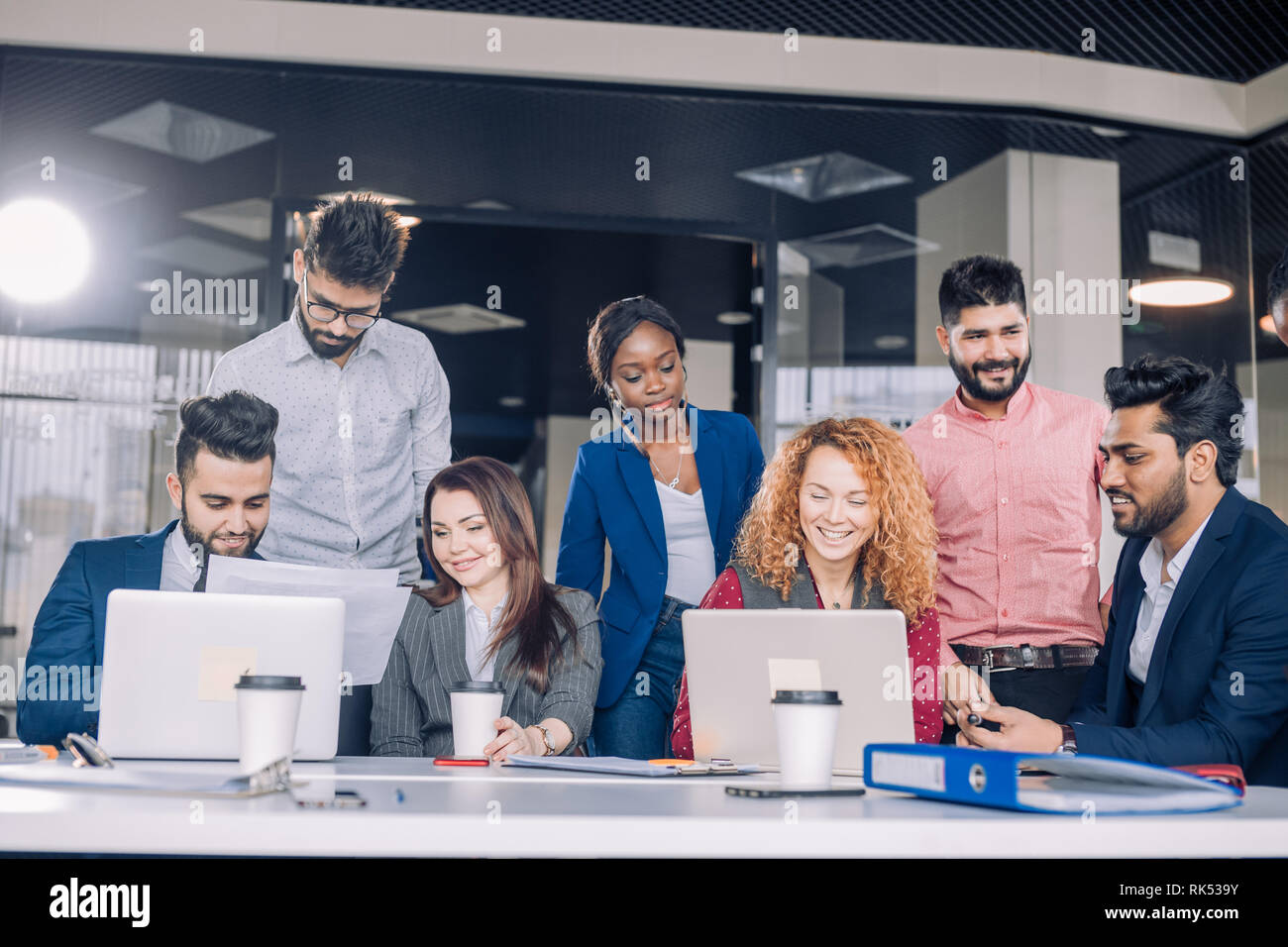 Woman showing coworkers something on laptop computer as they gather ...