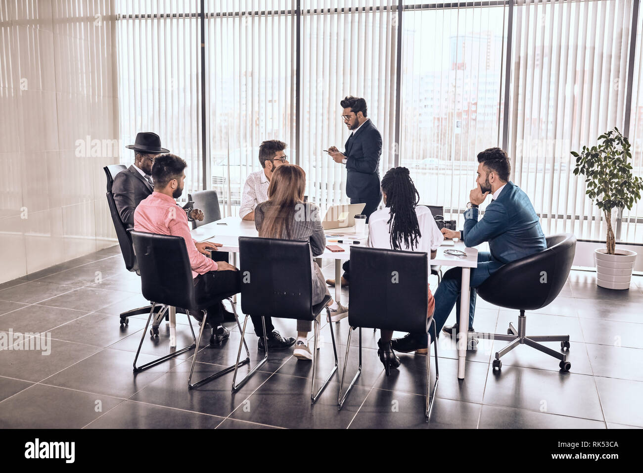 Indian boss making a phone call while his colleagues are waiting for ...