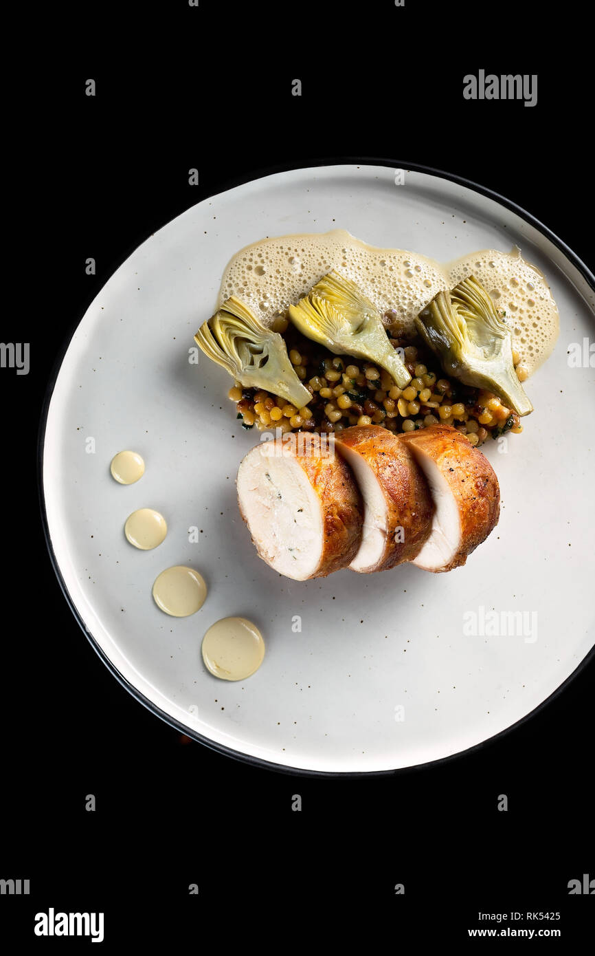 Chicken roulade with prosciutto, artichoke and emulsion on a white ...
