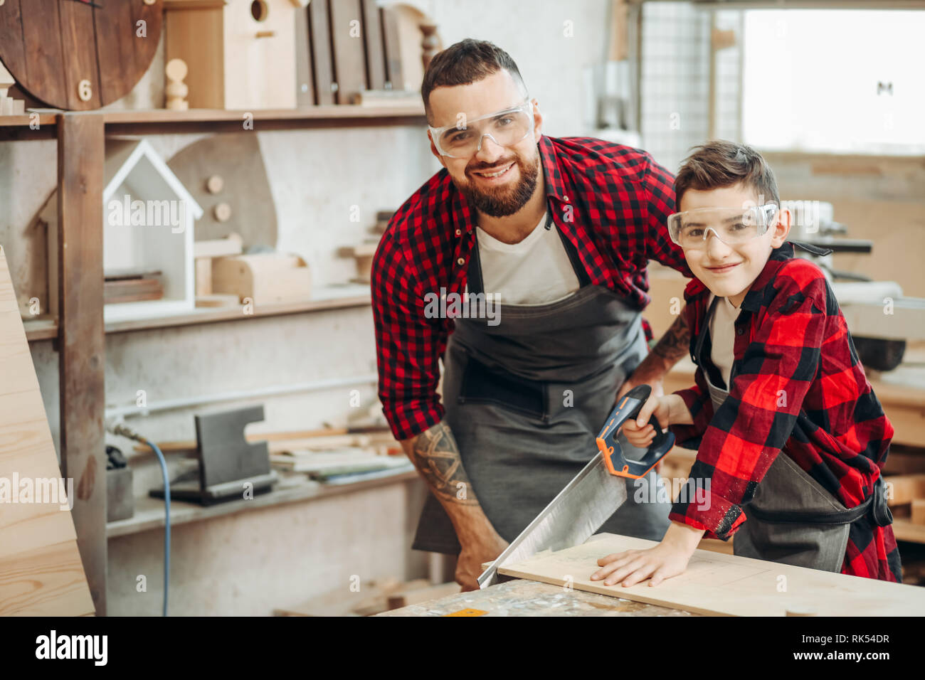 Experienced male teacher of carpentry skill acquaints a boy, with art ...