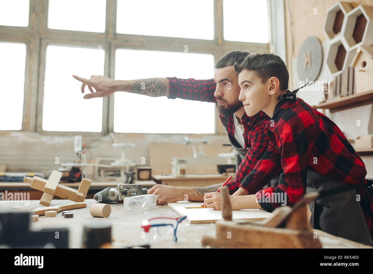 family, carpentry, woodwork and people concept - Carpenter pointing at ...
