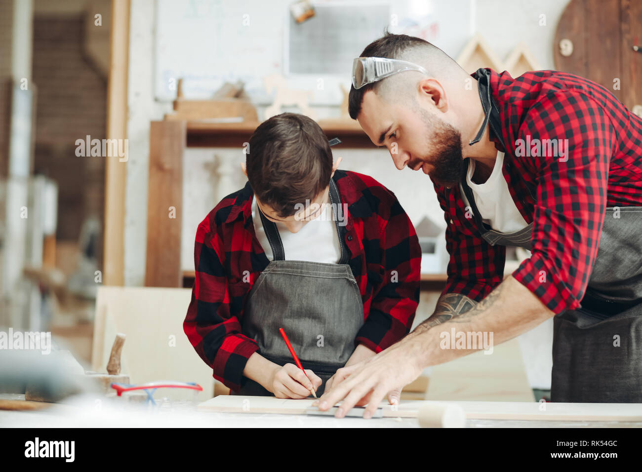 Hardworking little boy is busy taking measure and marking of wooden ...