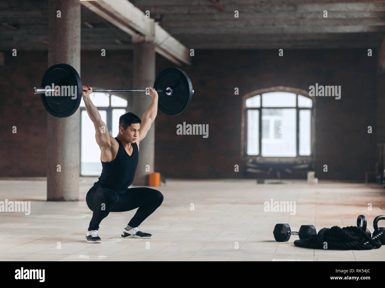 athlete doing weightlifting workout at gym, full length photo. copy ...