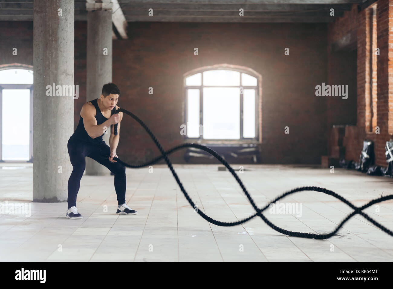 strong athlete doing exercise with battle rope at fitness gym. side ...